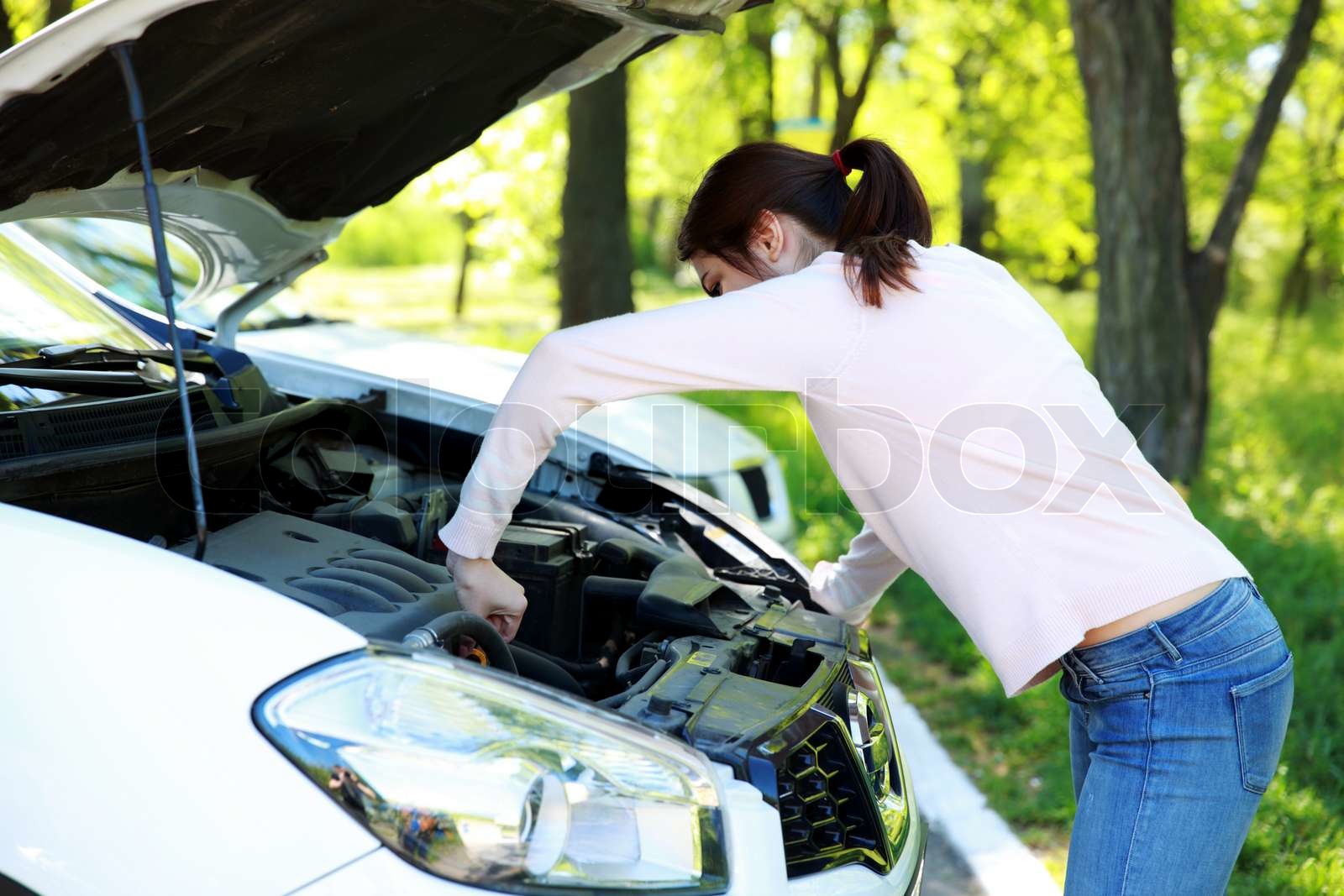 Beautiful woman checking her car engine | Stock image | Colourbox