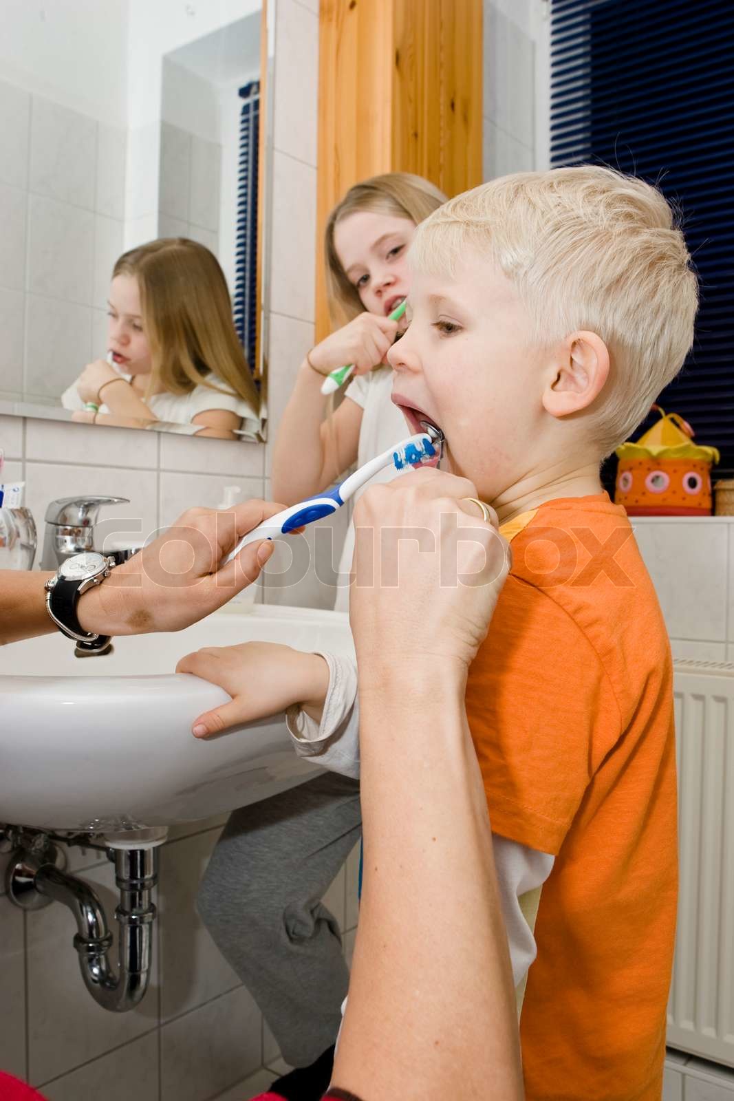 A young boy getting help to brush his teeth | Stock image | Colourbox