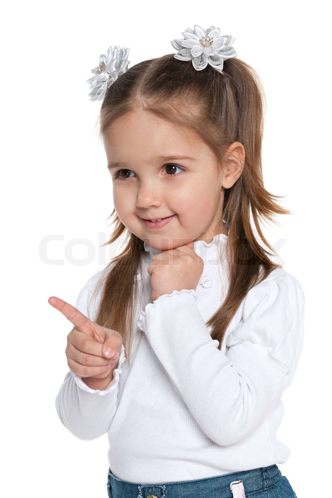 Smiling little girl shows her finger to the side | Stock image | Colourbox