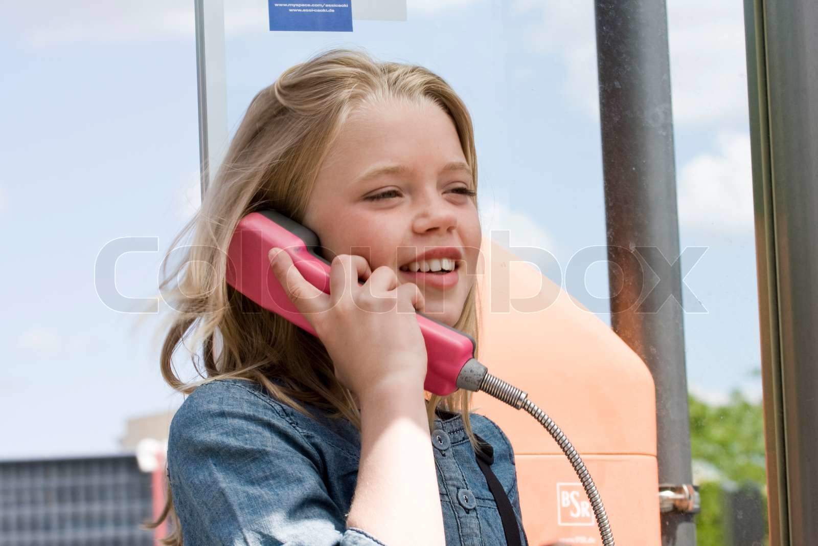 A teenage girl using a public phone | Stock image | Colourbox