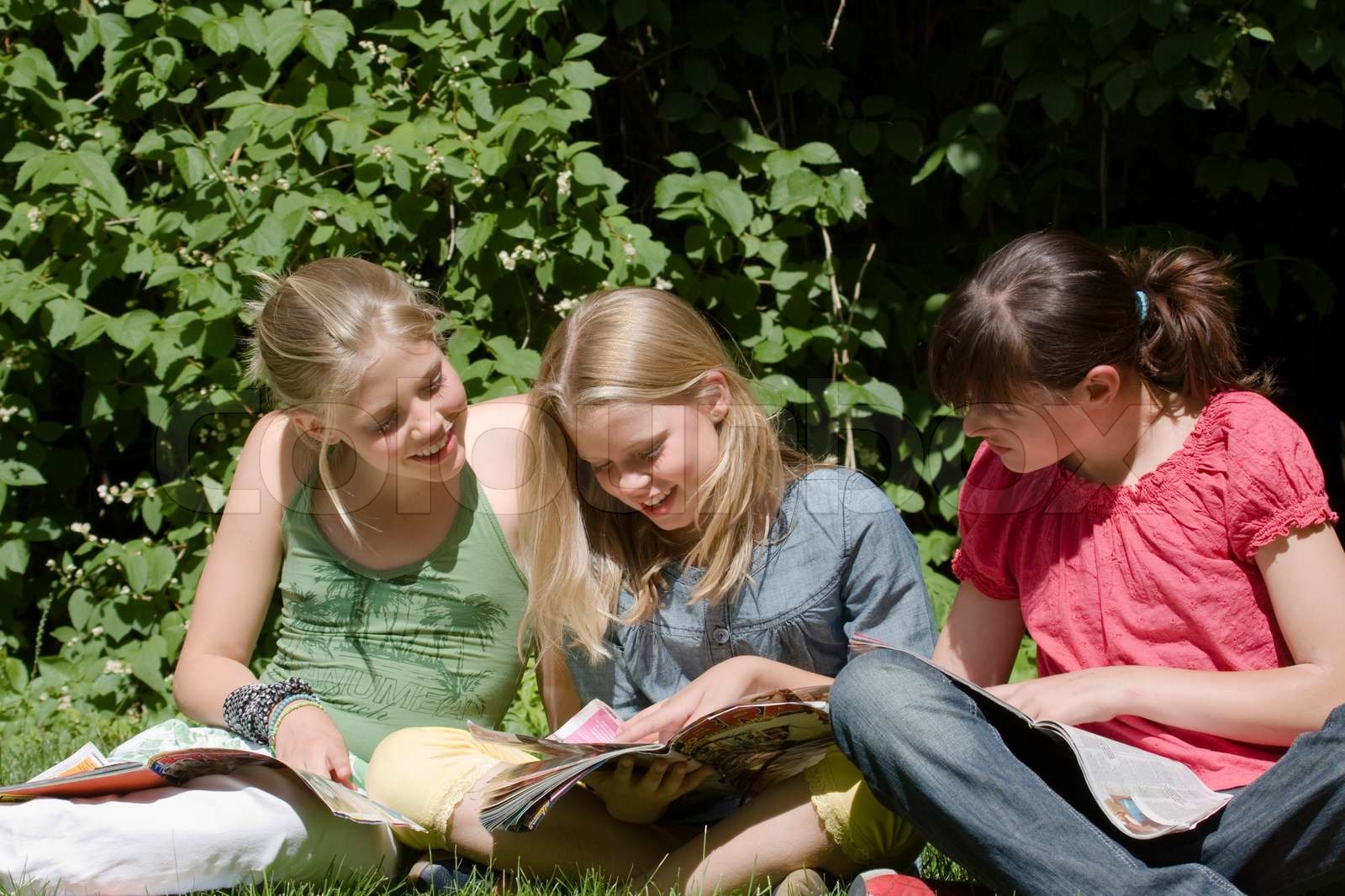 Three teenage girls reading a gossip magazine | Stock image | Colourbox