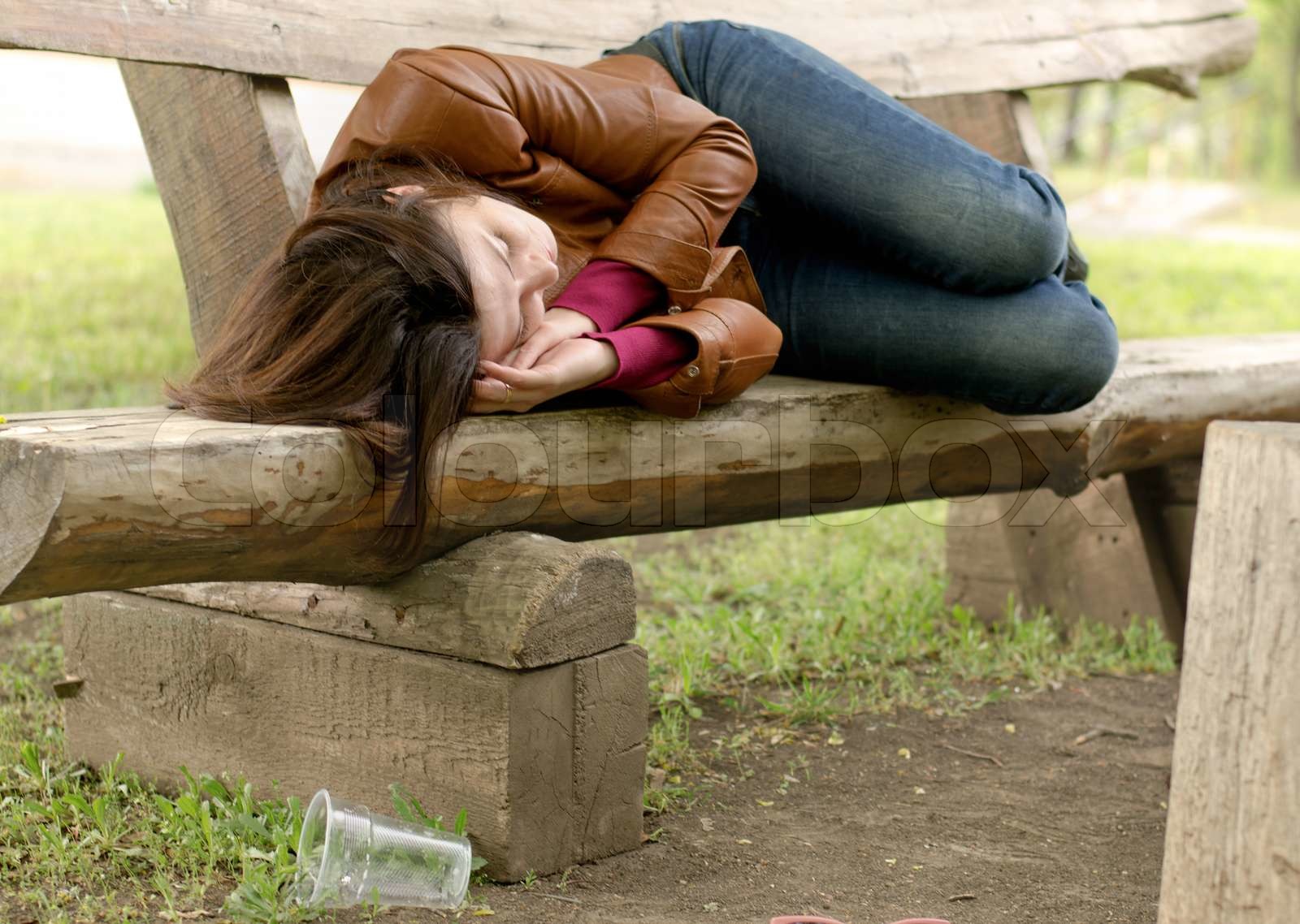Drunk woman sleeping it off on a wooden bench | Stock image | Colourbox