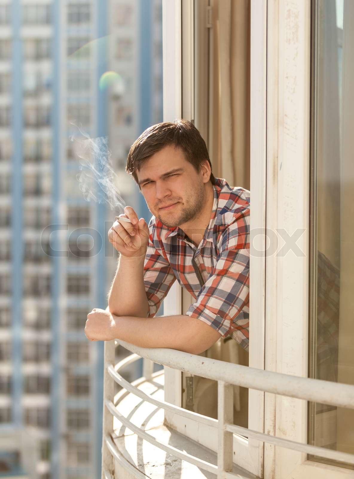 young man smoking cigarette on balcony | Stock image | Colourbox