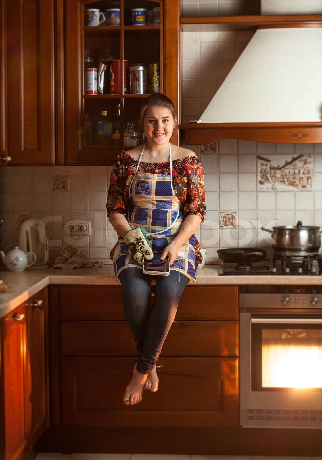 woman sitting on tabletop while cooking dinner in oven | Stock image ...