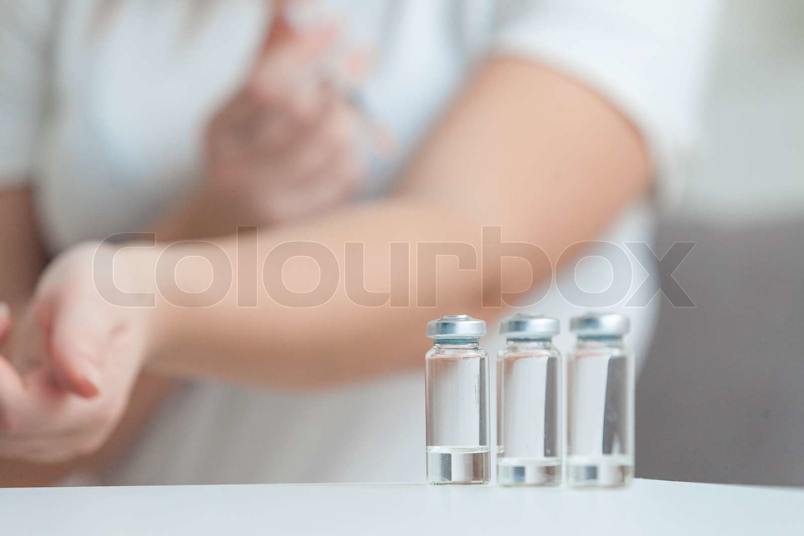 Woman doing injection behind empty ampules | Stock image | Colourbox