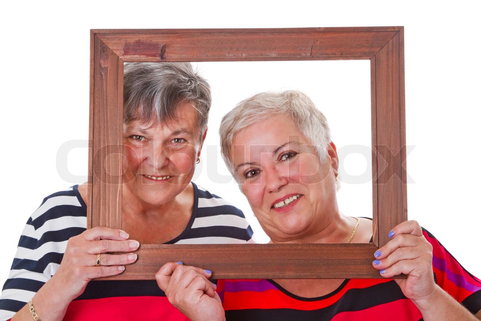 Two senior women looking through a picture frame | Stock image | Colourbox