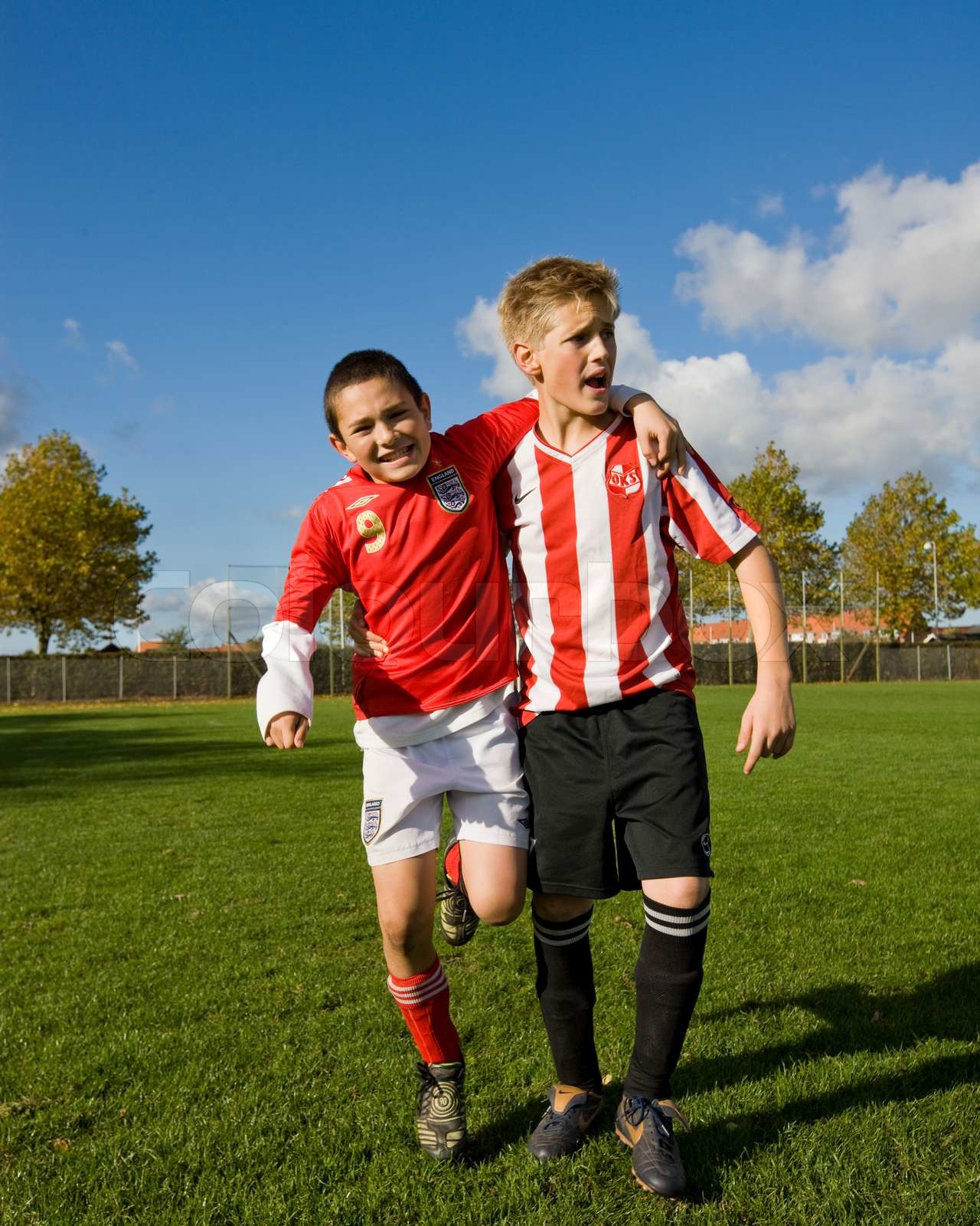 A young football player helping an injured player | Stock image | Colourbox