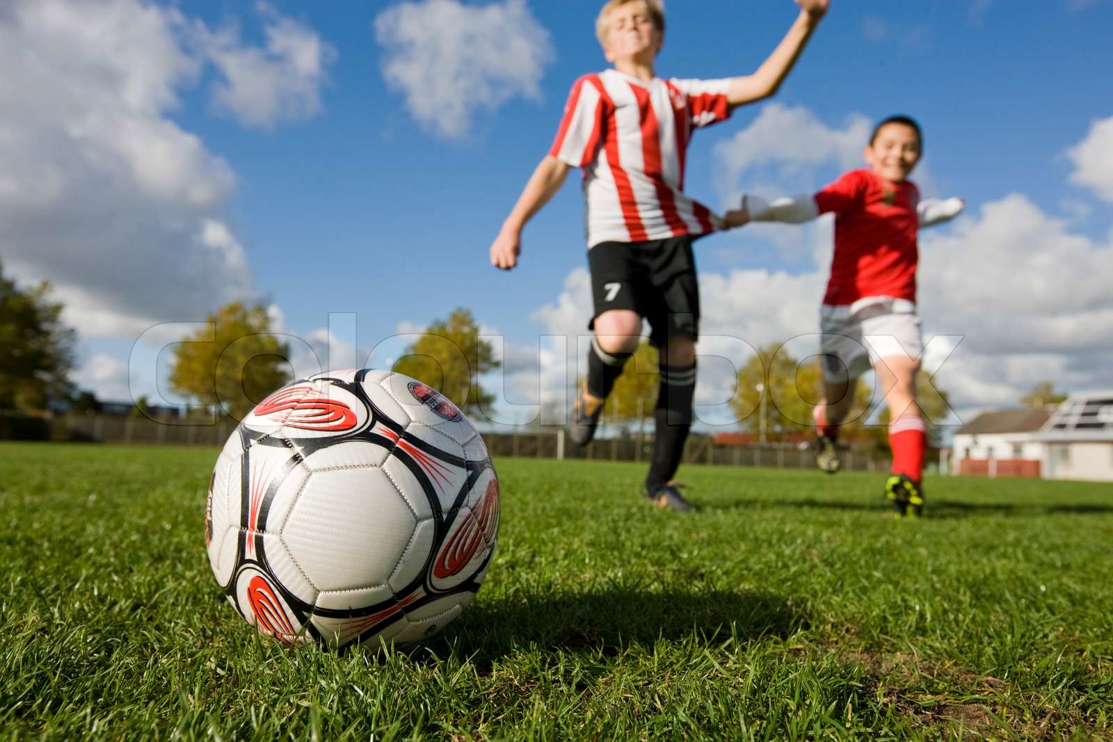 Two young football players running after a ball | Stock image | Colourbox