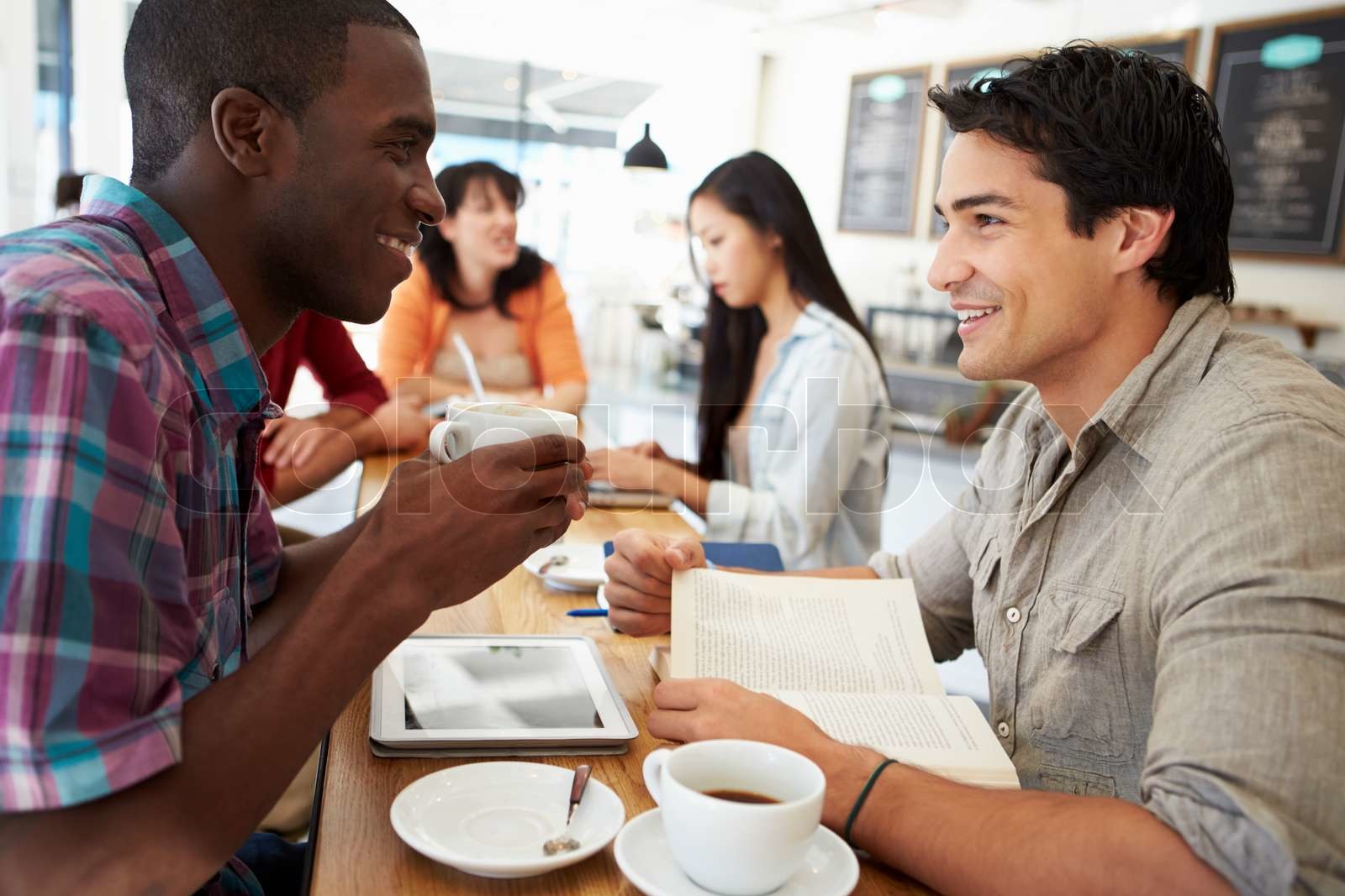 Two Male Friends Meeting In Busy Coffee Shop | Stock image | Colourbox