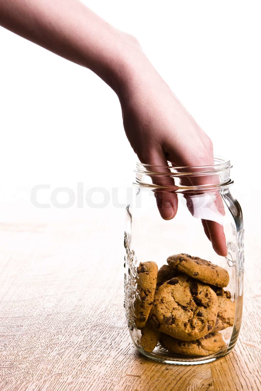 A hand getting a cookie from a jar | Stock image | Colourbox