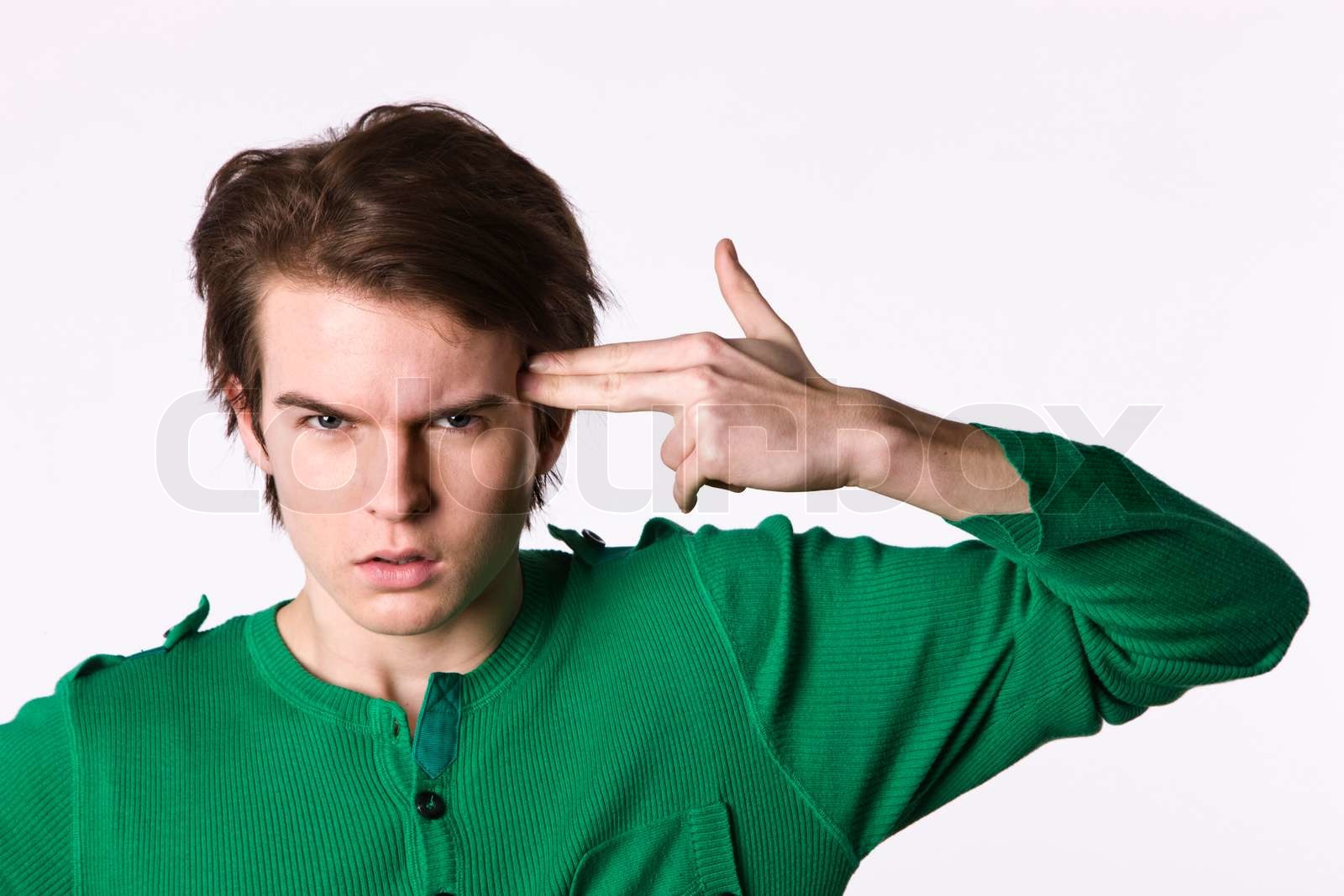 A teenage boy pointing a gun sign on his forehead | Stock image | Colourbox