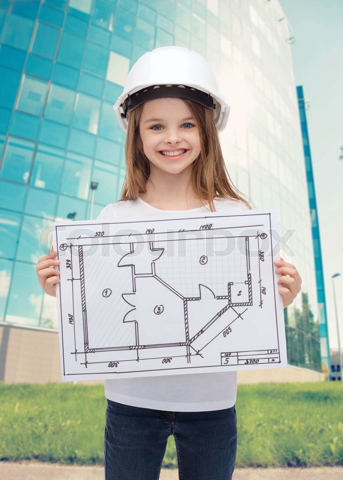 smiling little girl in helmet showing blueprint | Stock image | Colourbox