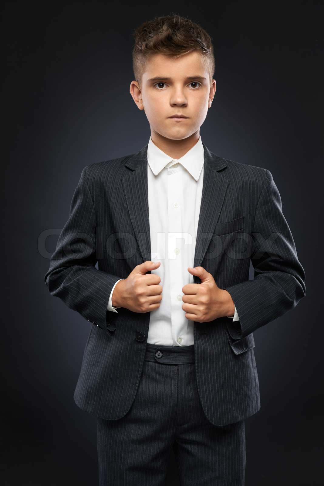 serious boy adjusts his black suit | Stock image | Colourbox