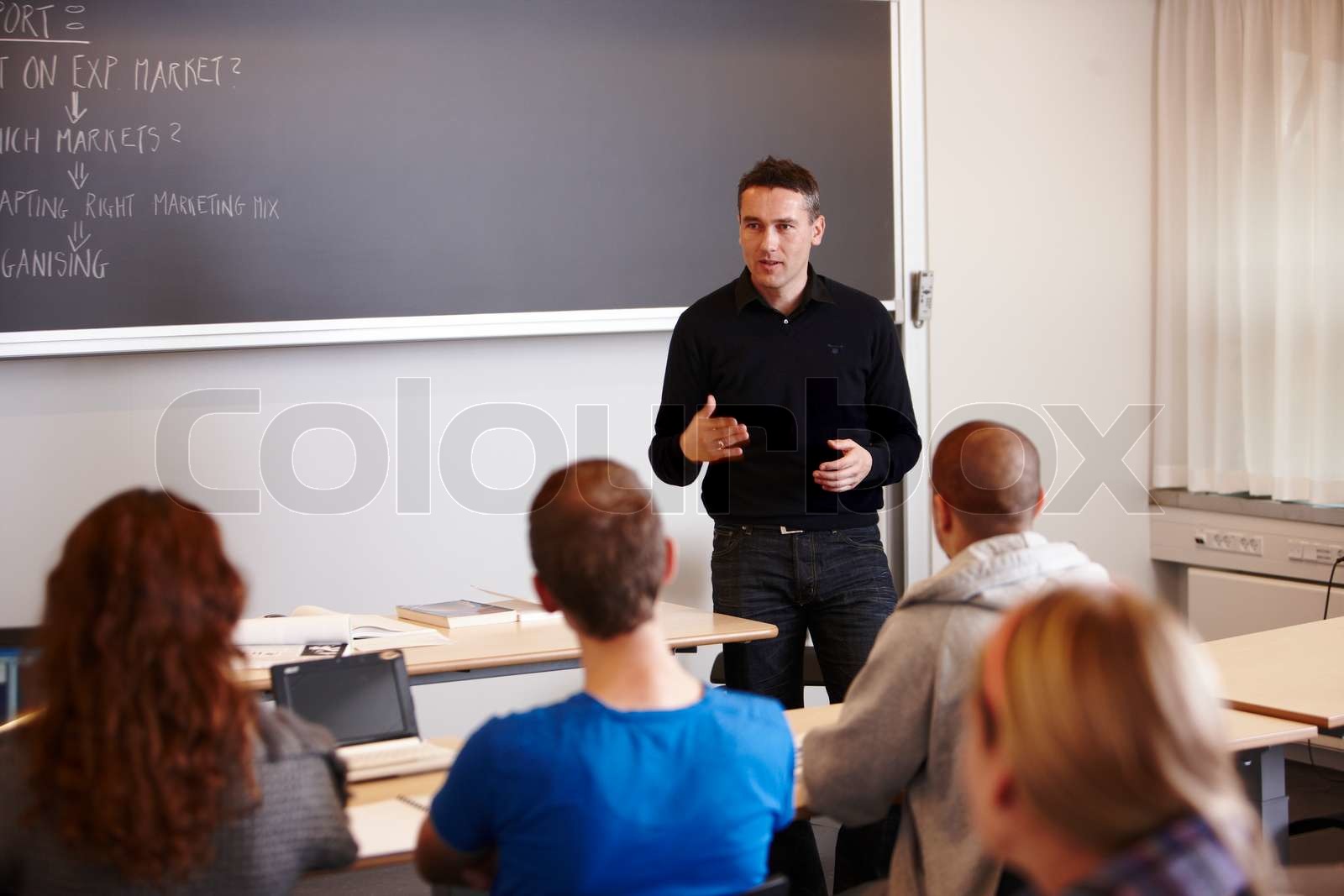 A school professor lecturing his students in a university auditorium ...