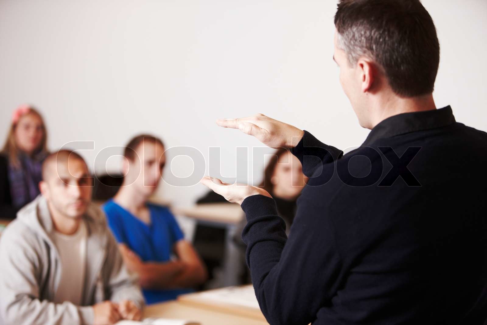 A school professor lecturing his students in university auditorium ...