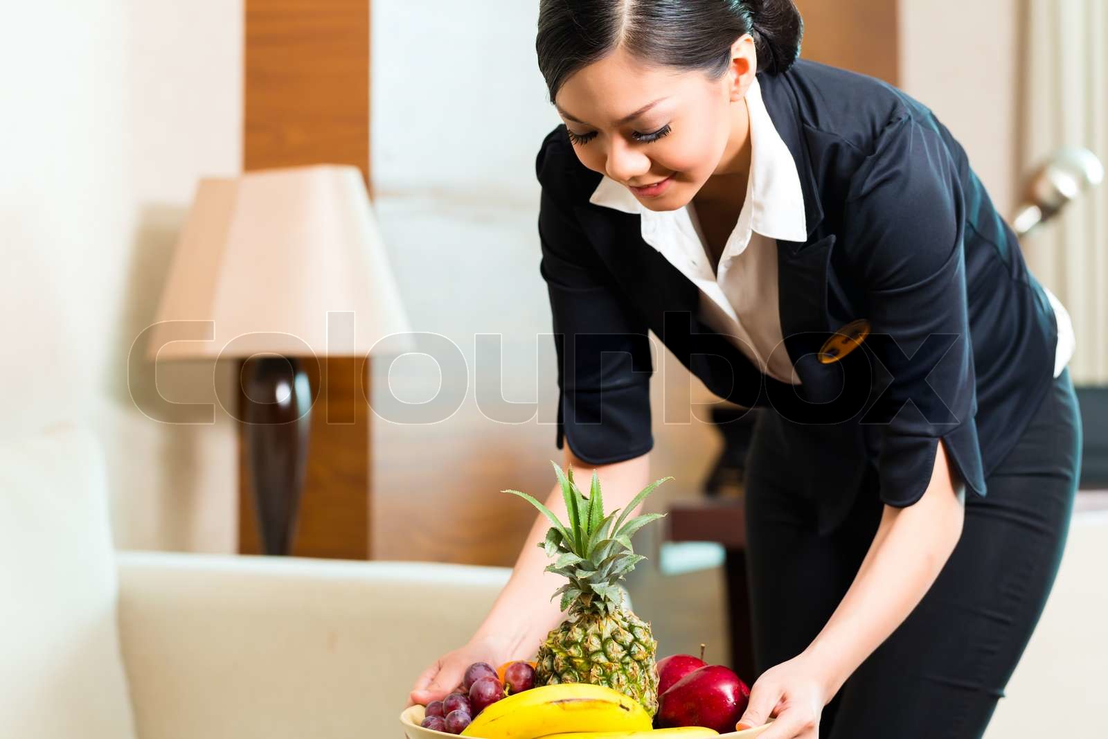 Asian Chinese hotel housekeeper placing fruit | Stock image | Colourbox