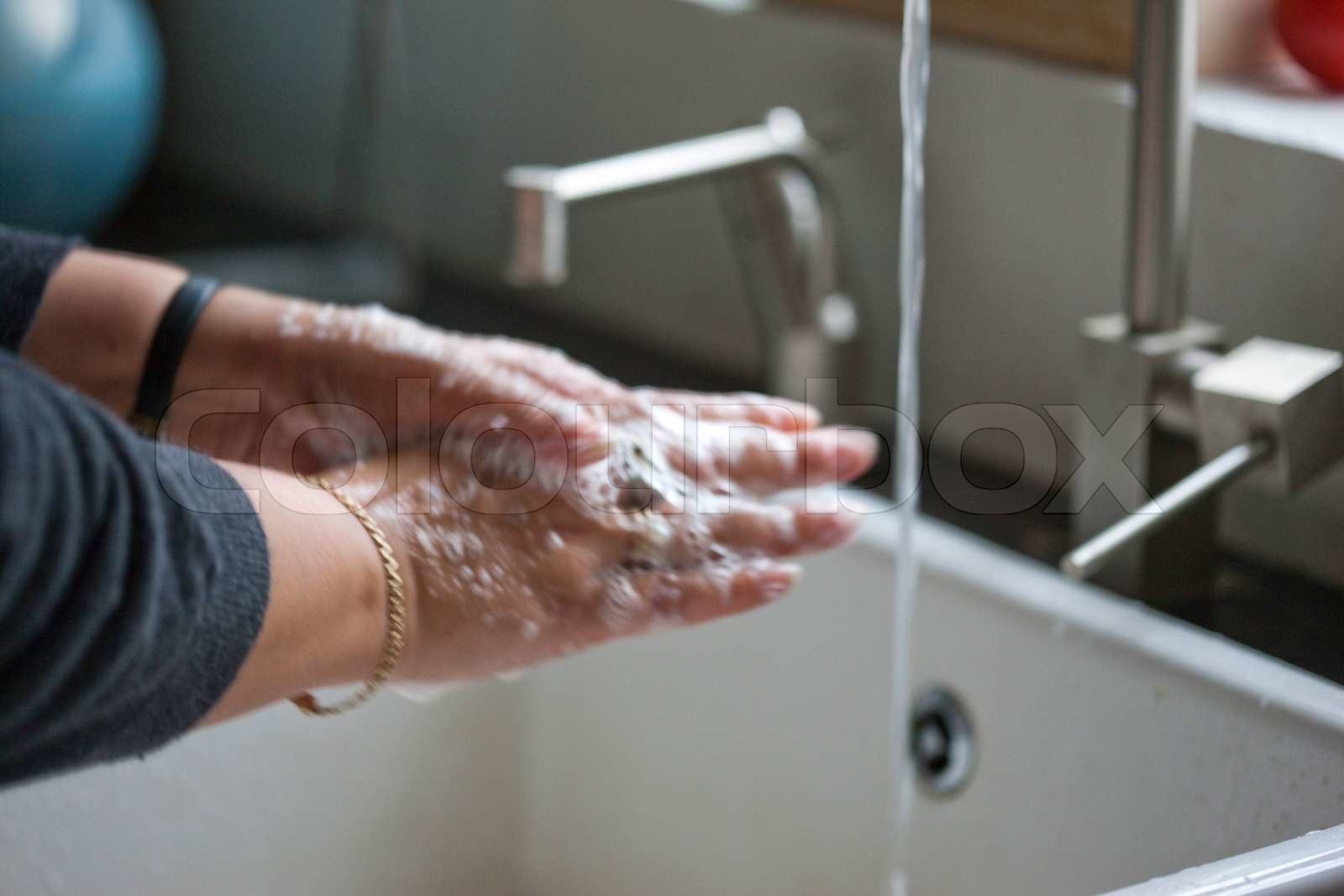 A woman washing her hands in the kitchen sink | Stock image | Colourbox