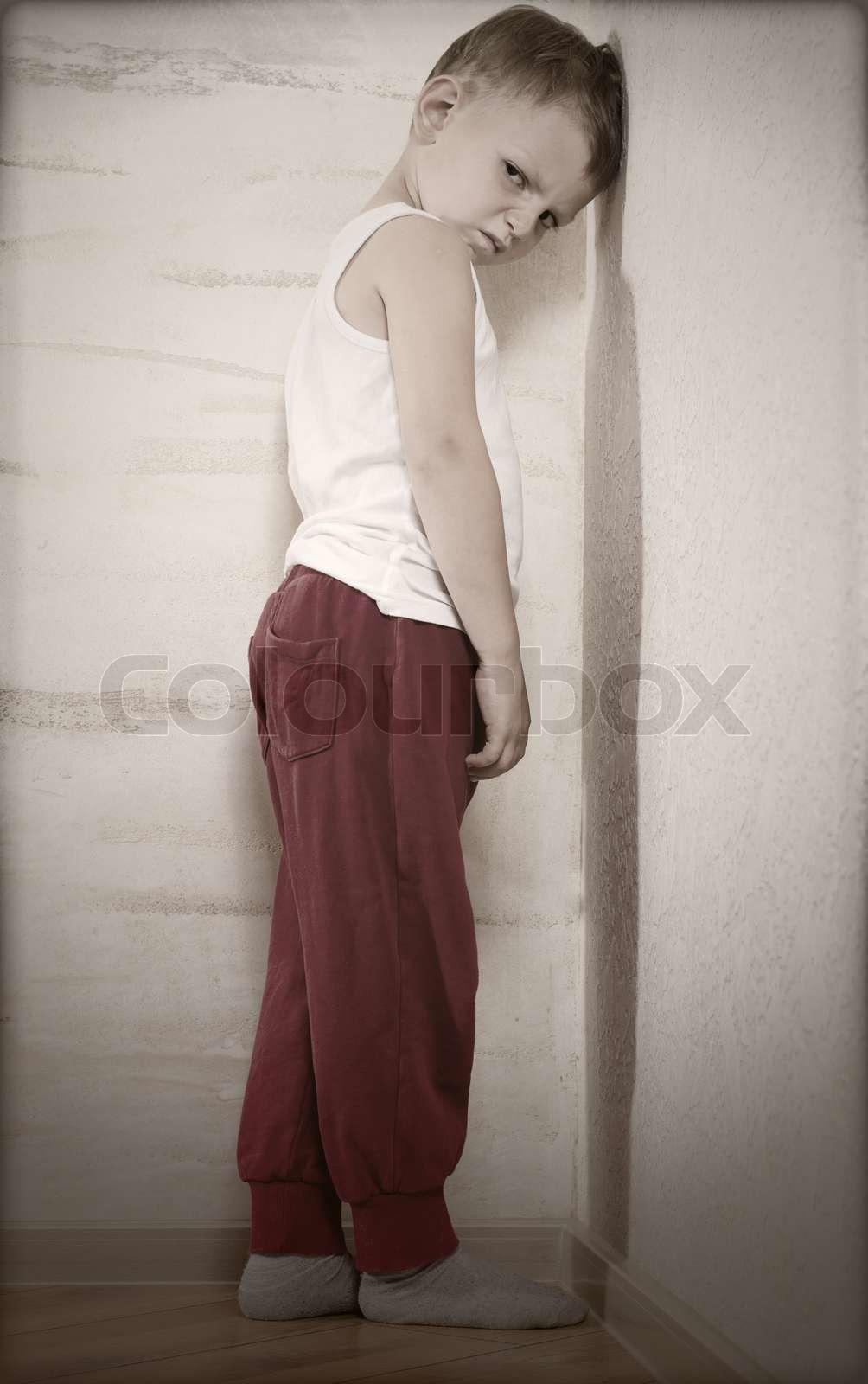 Little boy standing in a corner sulking | Stock image | Colourbox