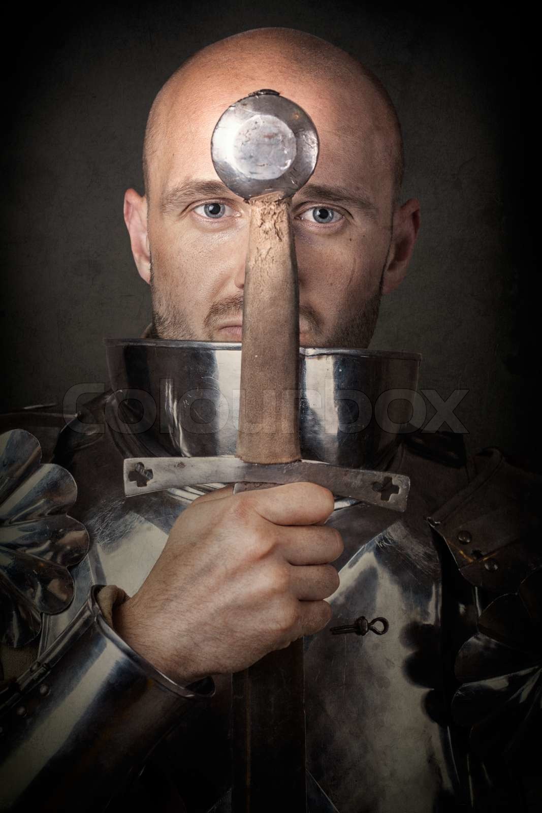 knight wearing armor and holding two-handed sword in front of his face ...