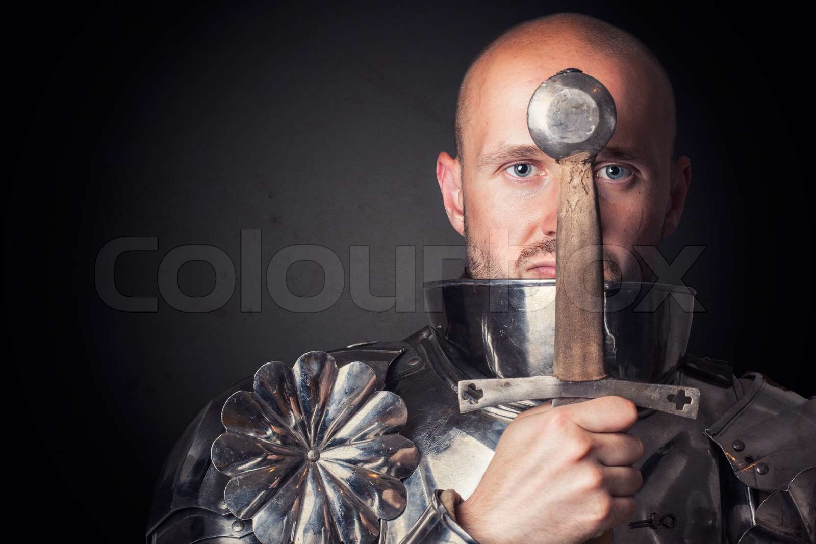 knight wearing armor and holding two-handed sword in front of his face ...