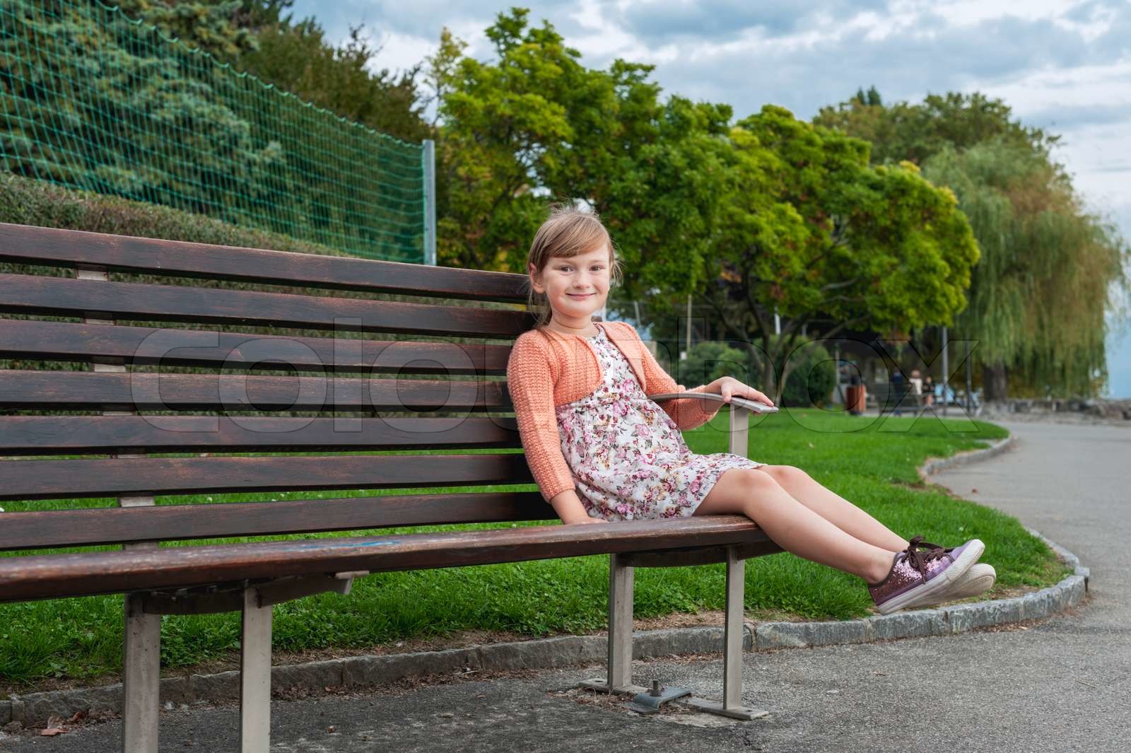 Outdoor portrait of a cute little girl sitting on a bench | Stock image ...