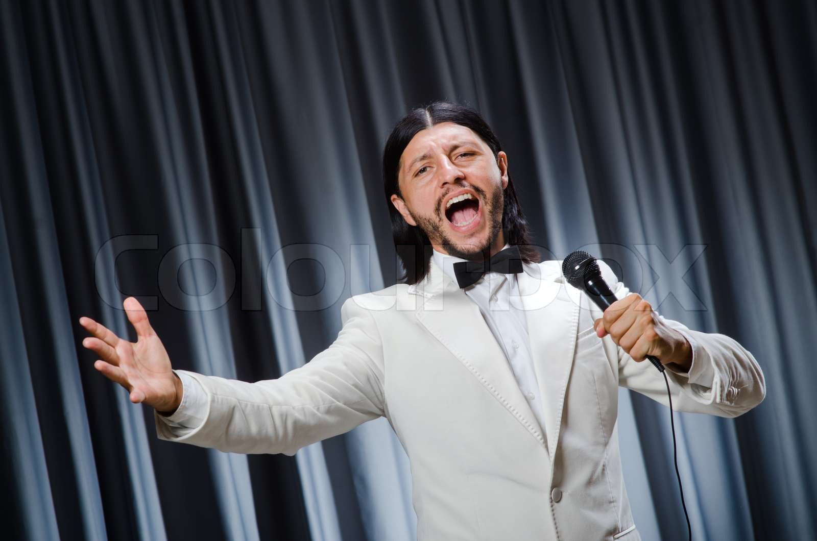 Man singing in front of curtain in karaoke concept | Stock image ...