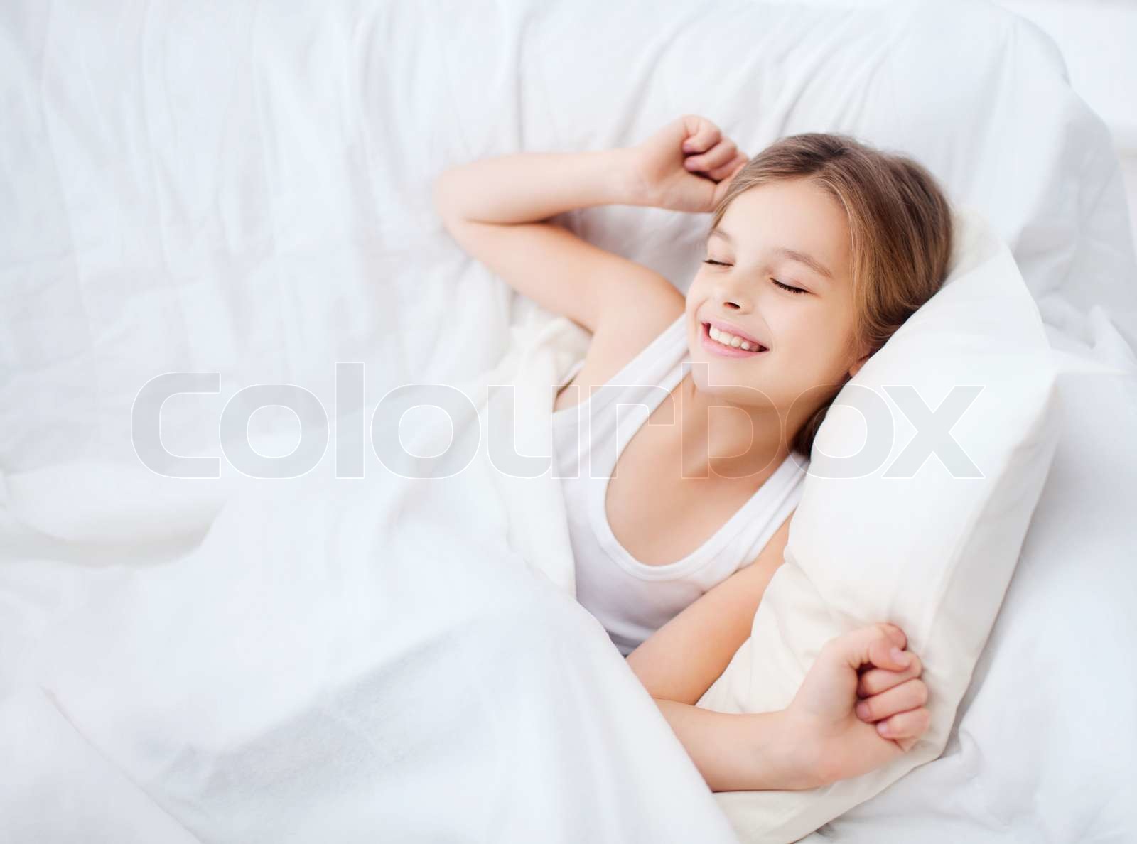 smiling girl child waking up in bed at home | Stock image | Colourbox