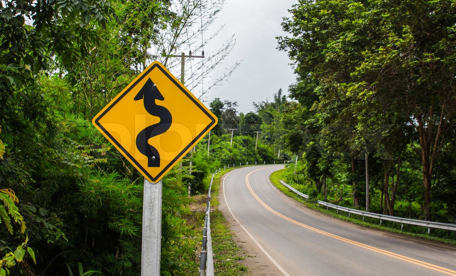 Curvy road sign to the mountain in rural area | Stock image | Colourbox