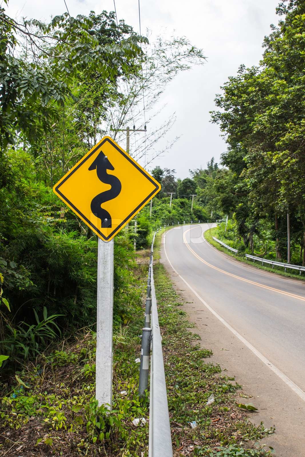 Curvy road sign to the mountain in rural area | Stock image | Colourbox