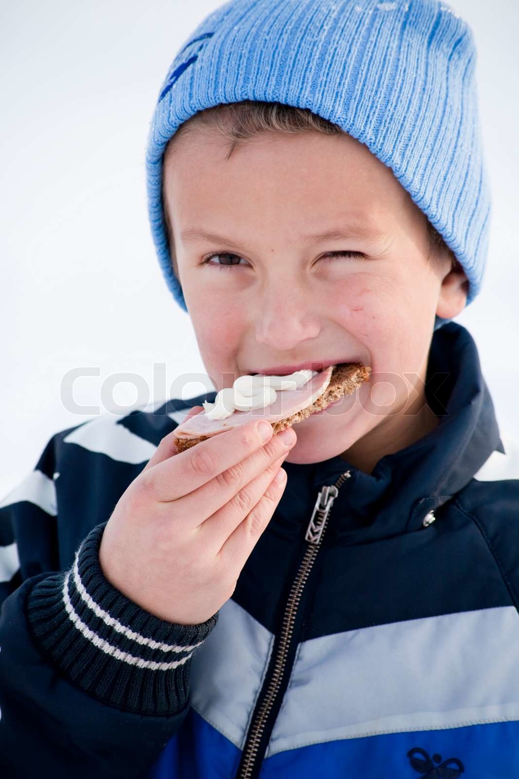 En lille dreng i vintertøj der spiser frokost udendørs | Stock foto ...