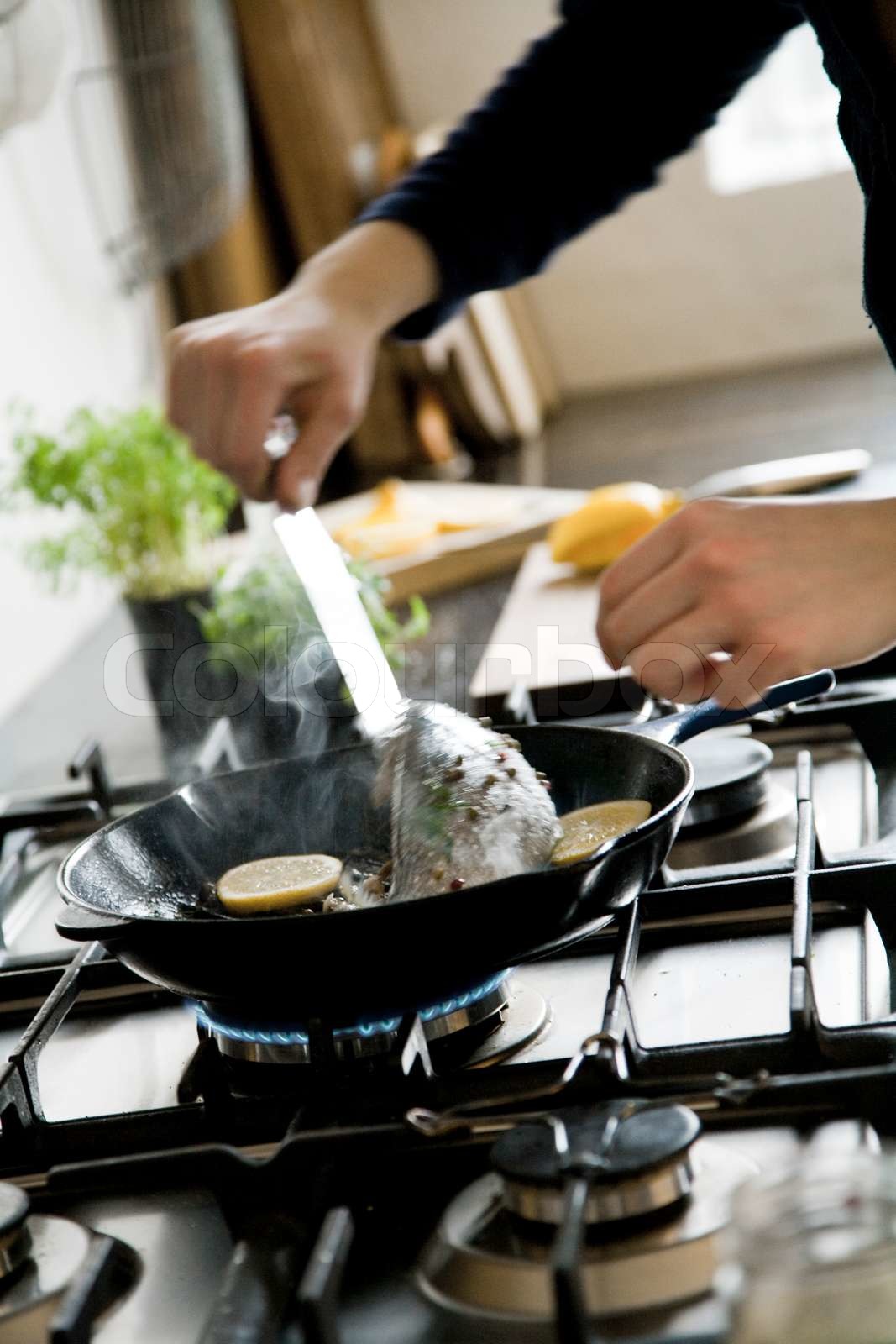 A woman frying fish on a gas stove | Stock image | Colourbox