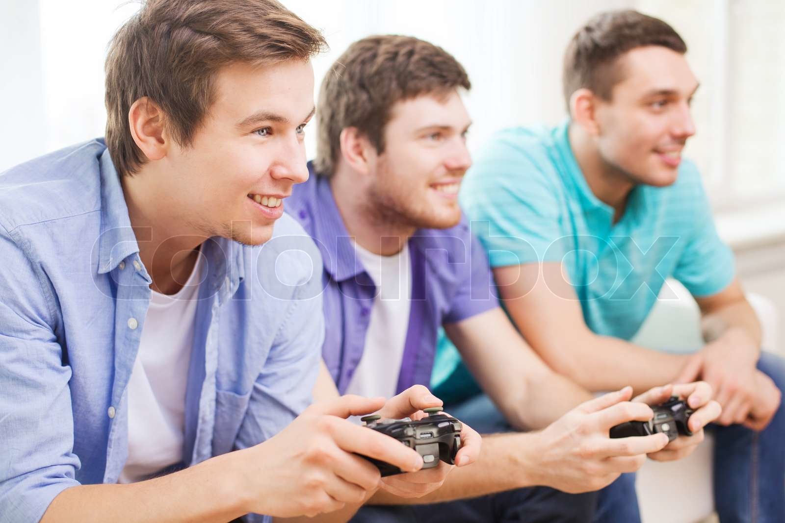 smiling friends playing video games at home | Stock image | Colourbox