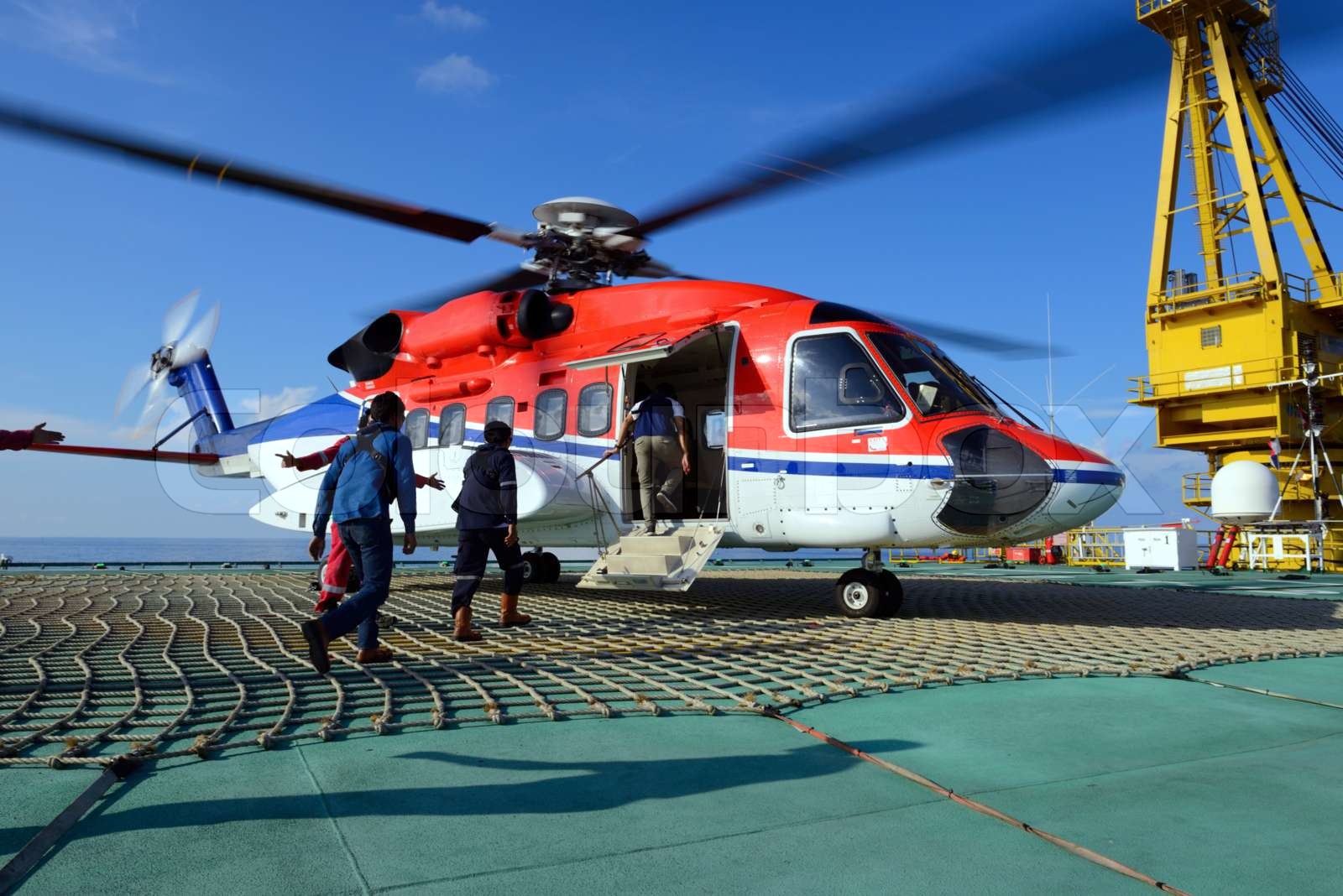 The helicopter landing officer take care passenger to embark helicopter ...