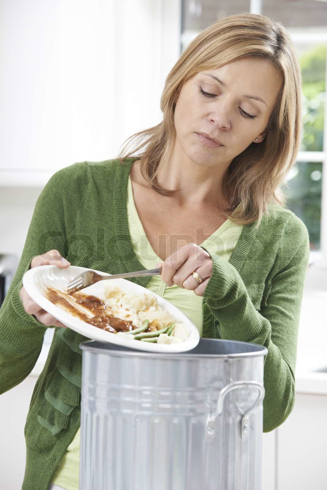 Woman Scraping Food Leftovers Into Garbage Bin | Stock image | Colourbox
