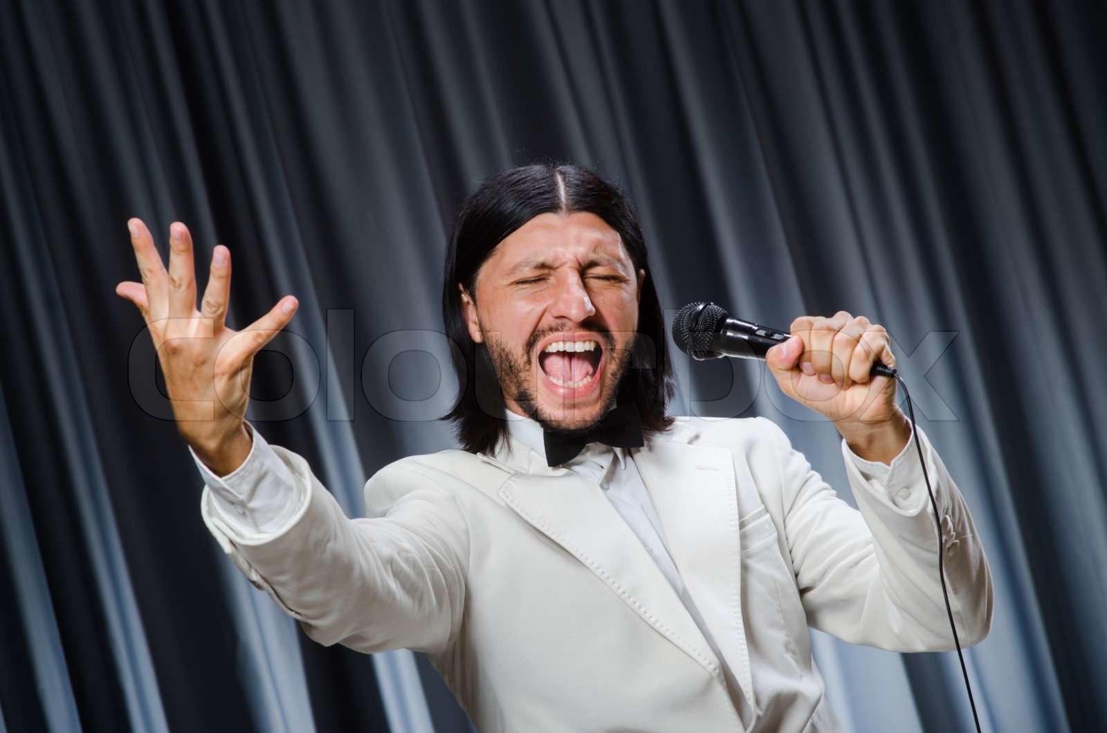 Man singing in front of curtain in karaoke concept | Stock image ...