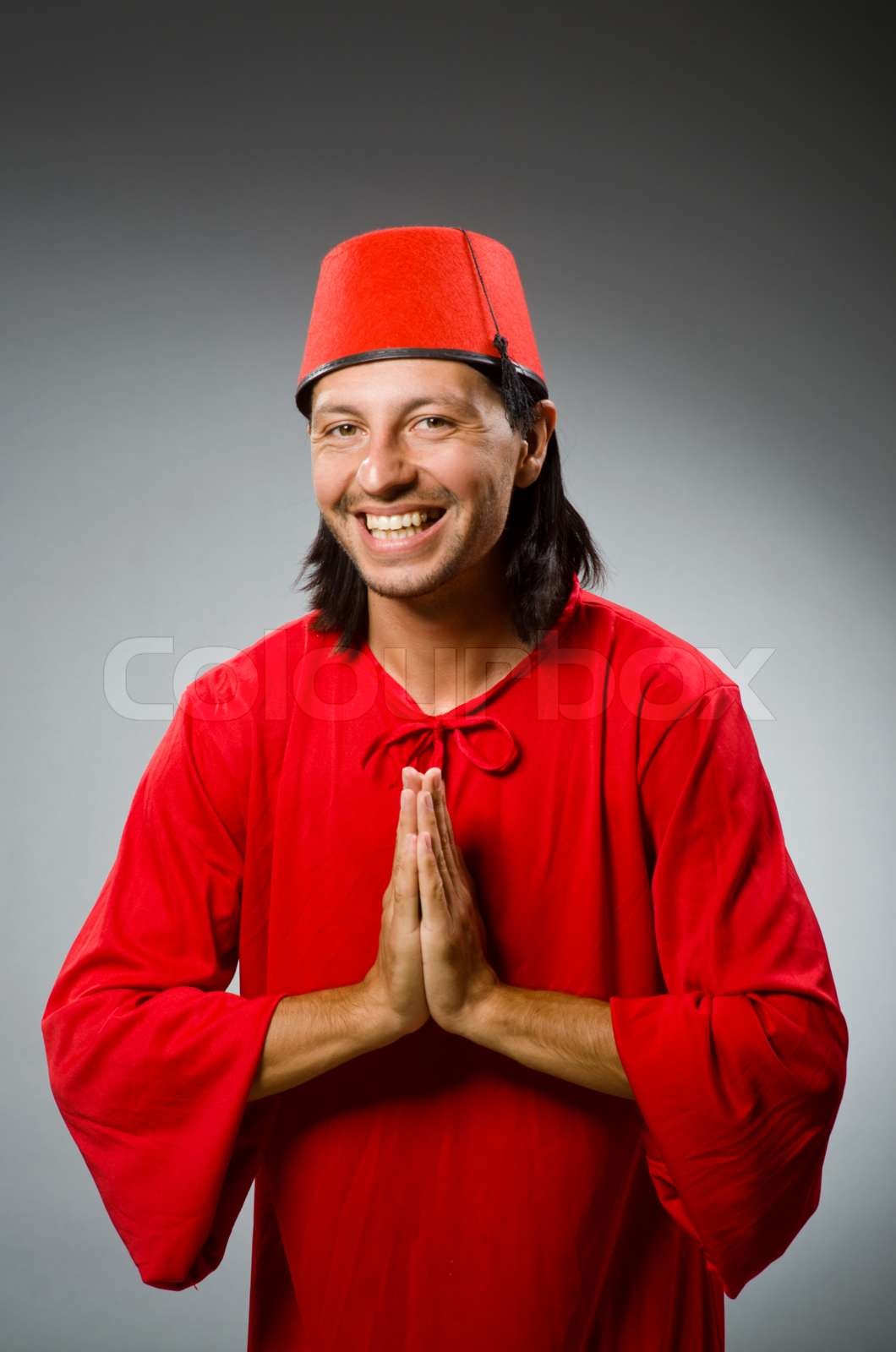 Man in red dress wearing fez hat | Stock image | Colourbox