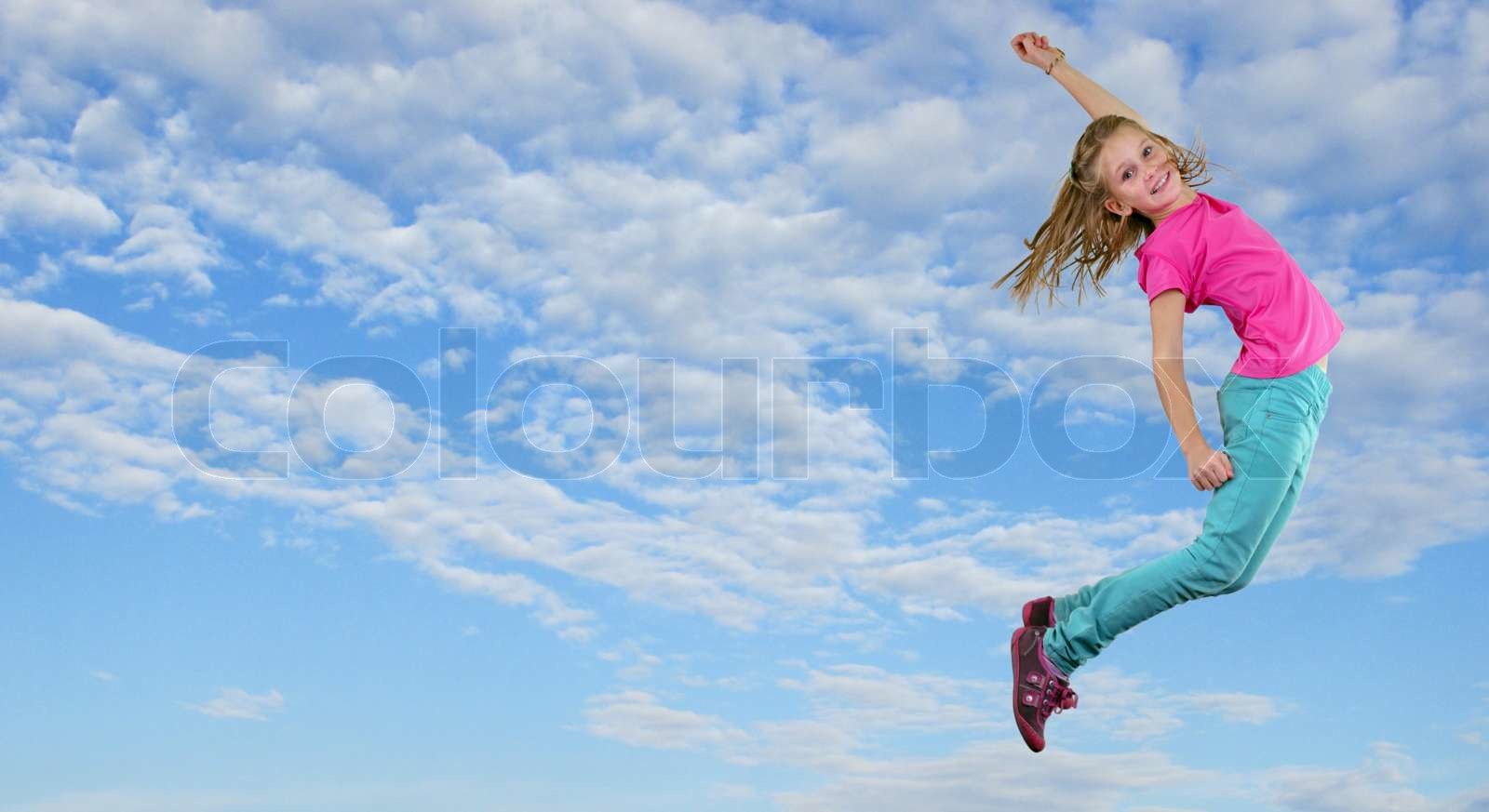 little girl jumping and dancing against blue cloudy sky | Stock image ...