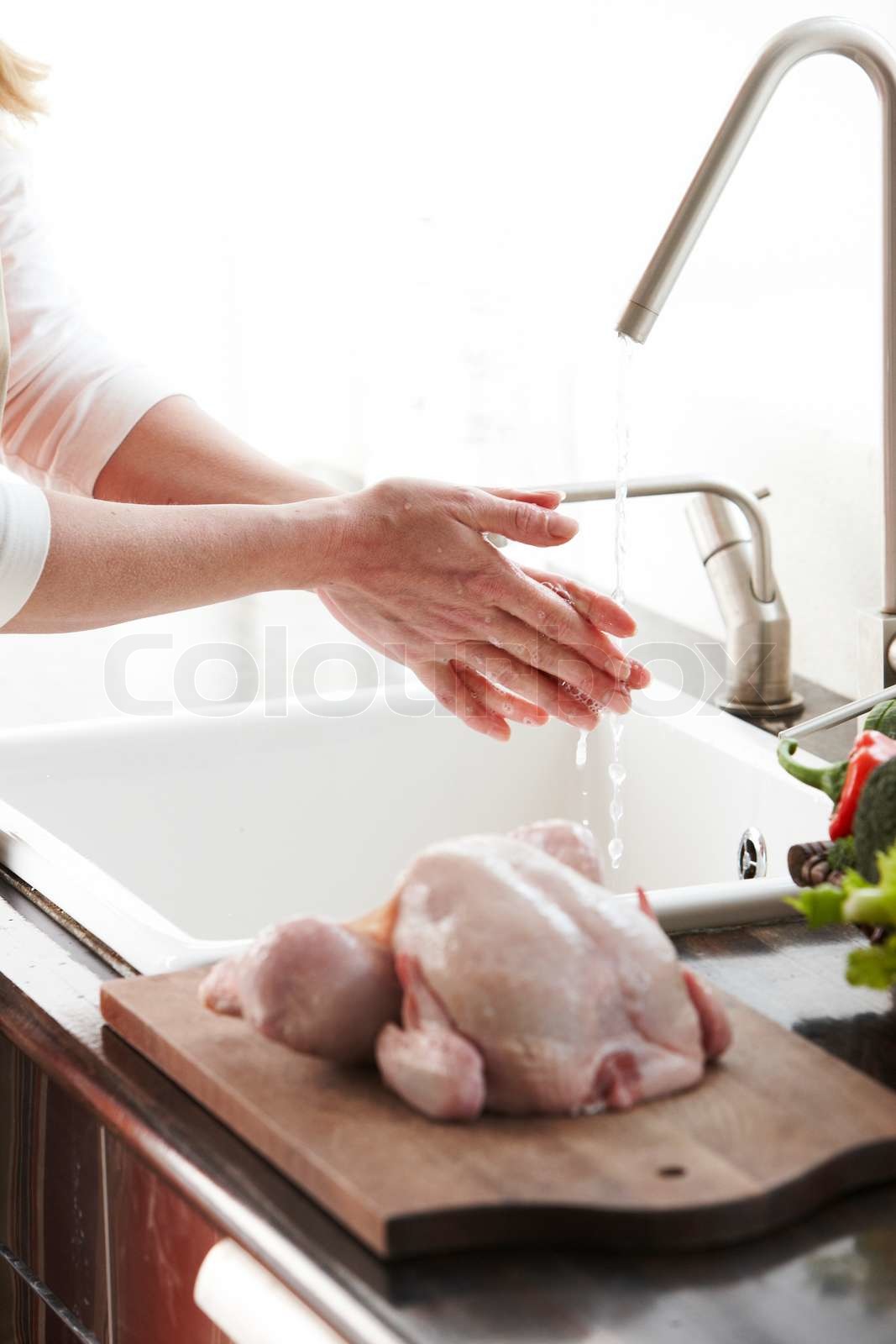 Female washing hands before preparing chicken for dinner in the kitchen ...