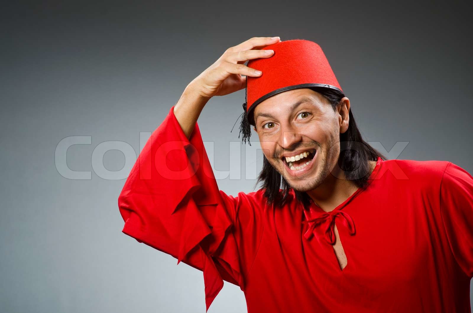 Funny man in red dress wearing fez hat | Stock image | Colourbox