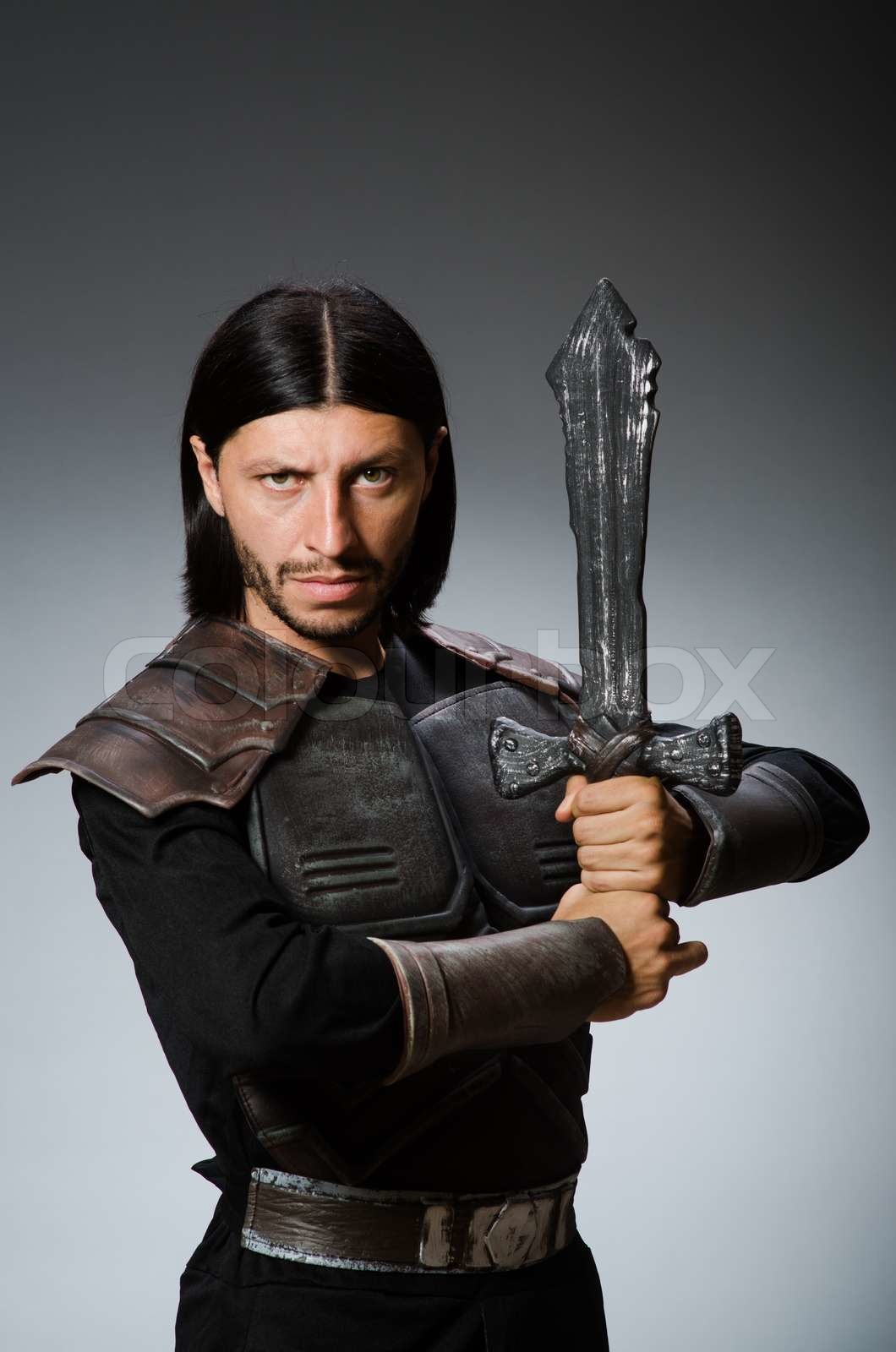 Angry knight with sword against dark background | Stock image | Colourbox