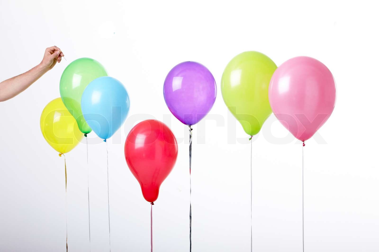 A person trying to pop a birthday balloon | Stock image | Colourbox