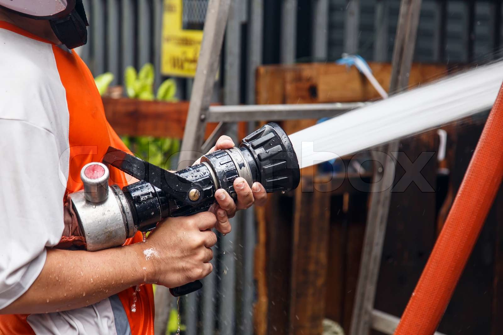 Fireman using water hose to prevent fire | Stock image | Colourbox