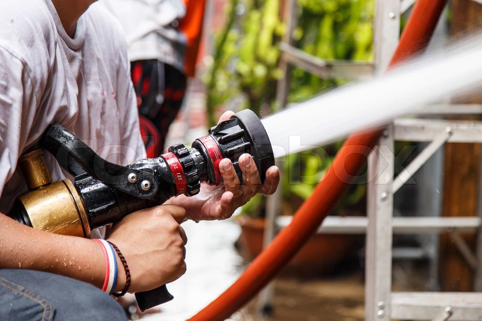 Fireman using water hose to prevent fire | Stock image | Colourbox