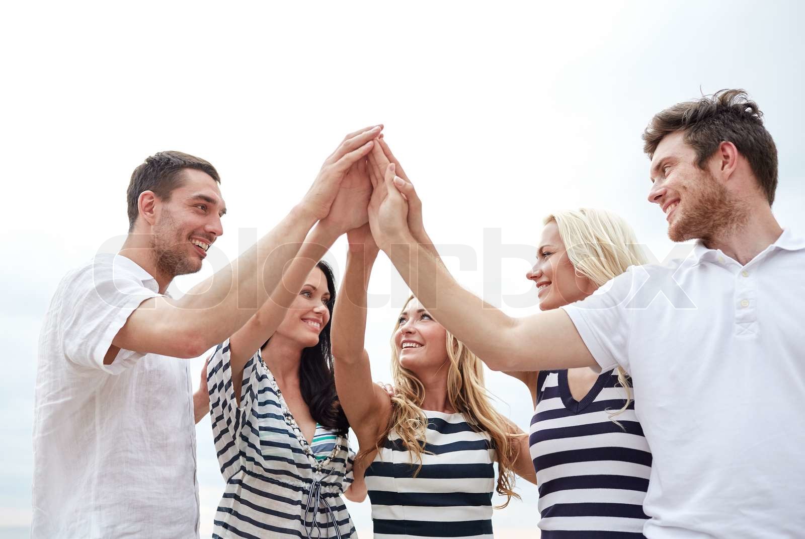 smiling friends making high five gesture outdoors | Stock image | Colourbox