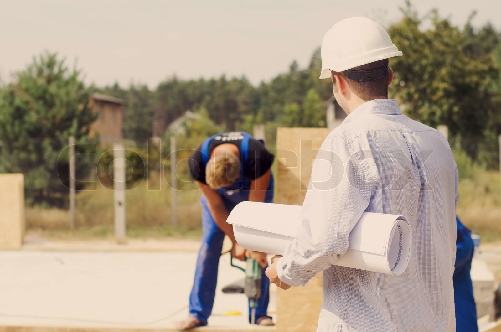 Architect standing watching the builders at work | Stock image | Colourbox