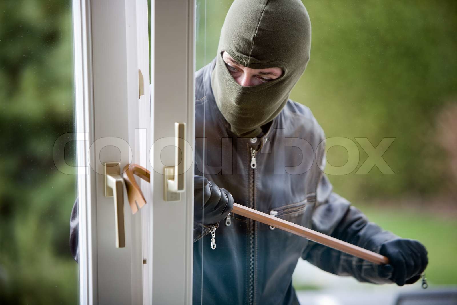 Burglar breaking into a house through the window | Stock image | Colourbox