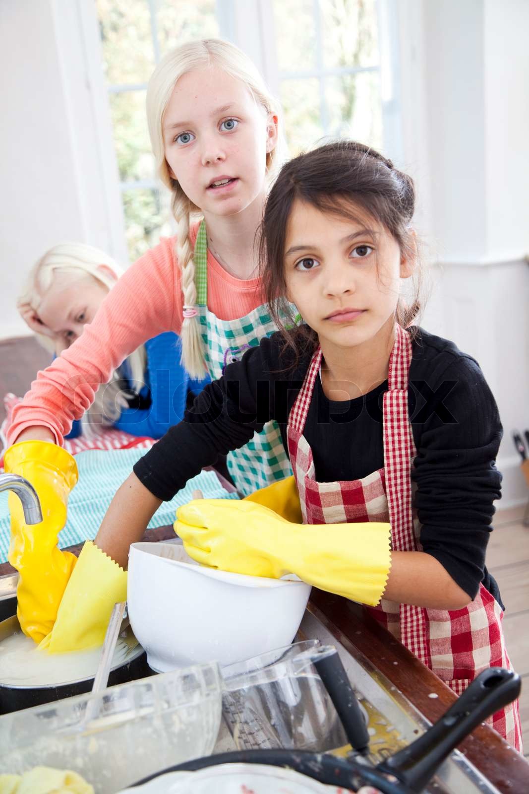 Two girls cleaning dirty kitchen wares | Stock image | Colourbox