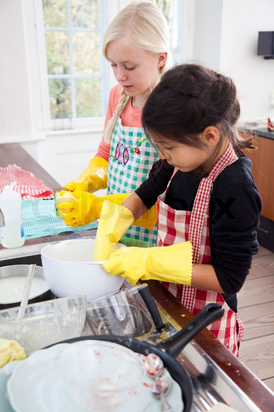 Two girls cleaning dirty kitchen wares | Stock image | Colourbox