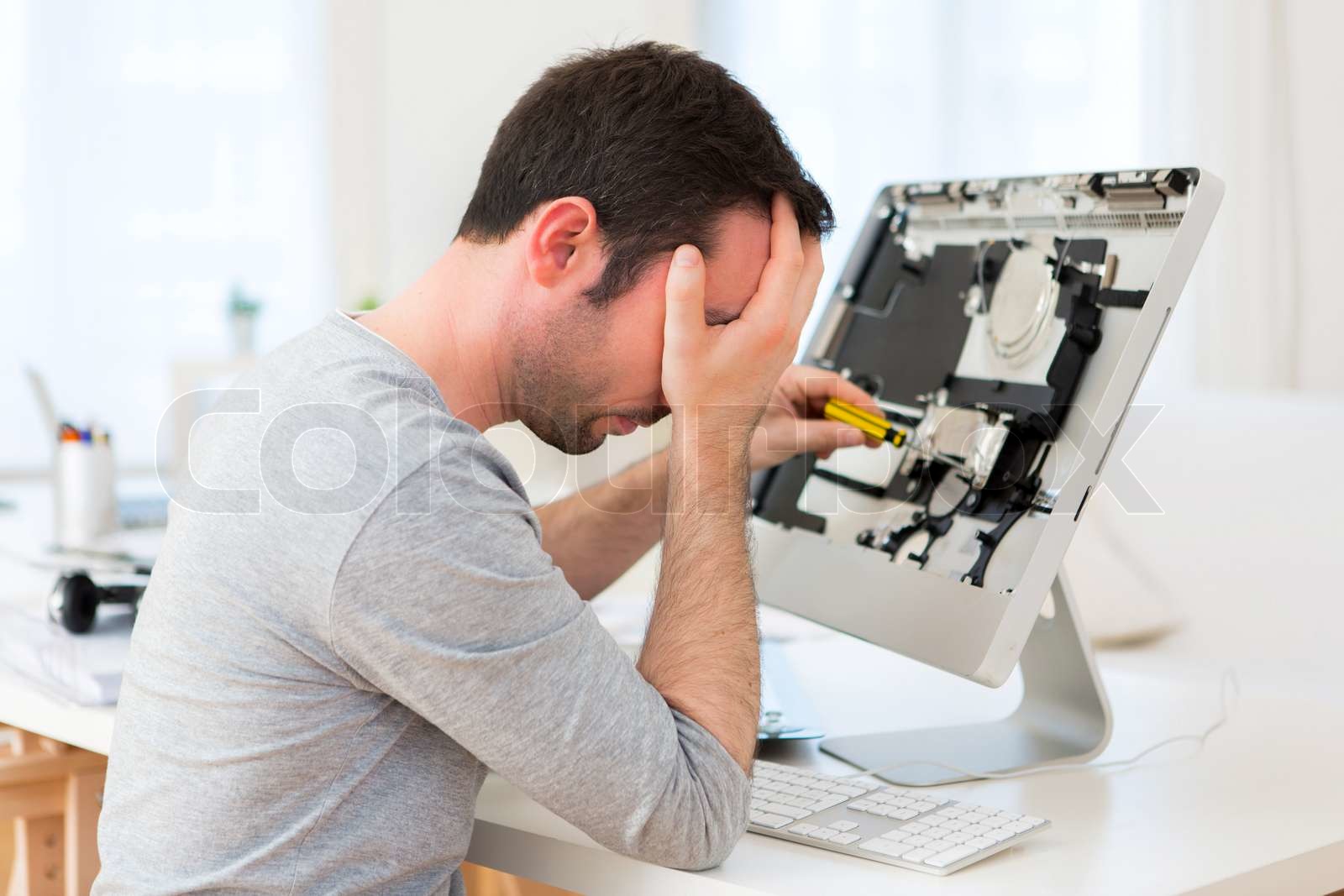 Young attractive man trying to repair computer | Stock image | Colourbox