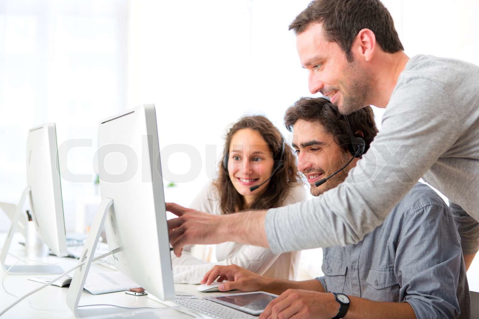 Group of people working around a computer | Stock image | Colourbox